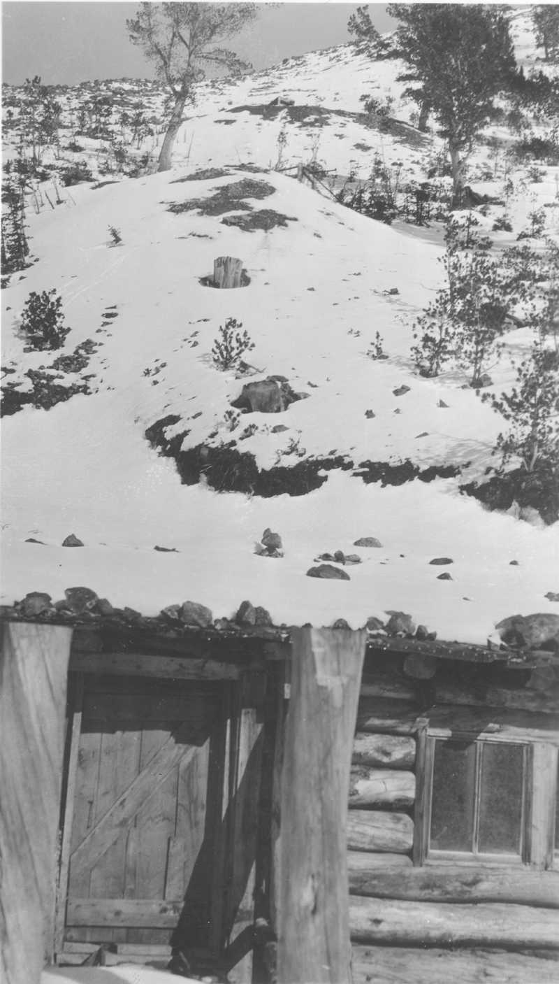 Close Up View of Front Door of Snow Covered Log Cabin Dugout