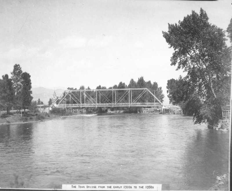 Metal truss bridge with trees along the bank in the early 20th century.
