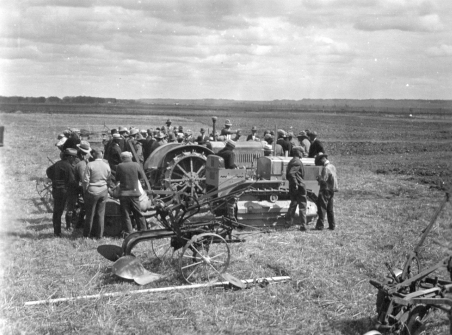 Men gathered around different tractors for a farm Demonstration