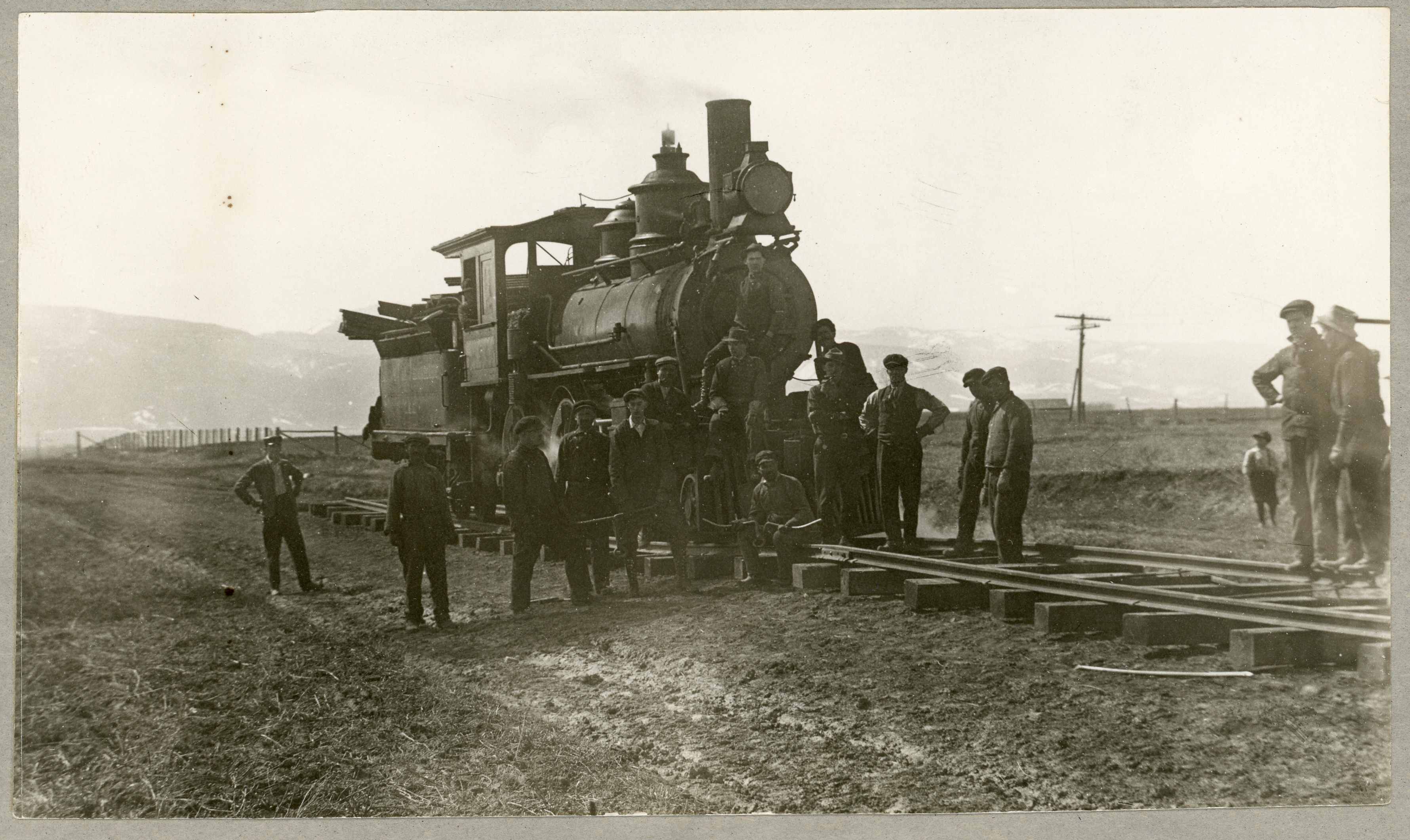 Men standing with locomotive engine kept at the edge of campus, 1917