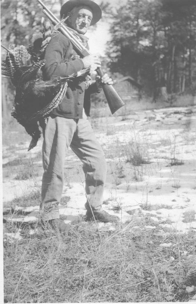 Photo of James W. Schultz carrying a shotgun and two turkeys over his ...
