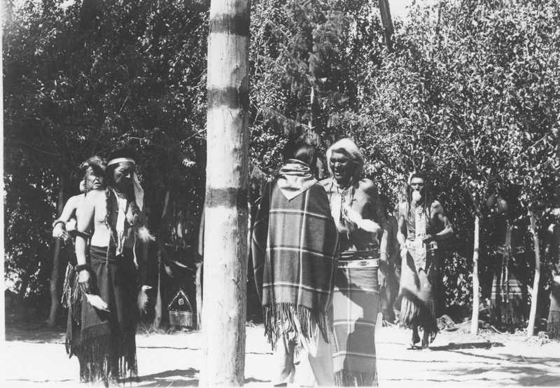 Photo of four men holding feathers face a women with her back to the ...